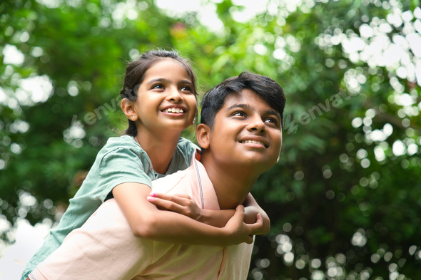 Indian big brother giving playful piggyback ride to his little sister ...