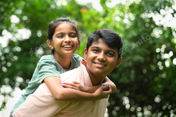 Indian big brother giving playful piggyback ride to his little sister ...