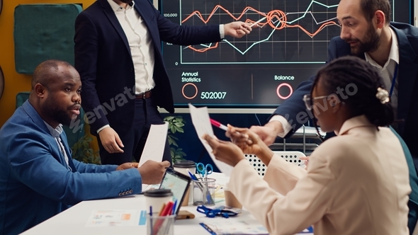 Project team colleagues examining sales infographics on presentation ...