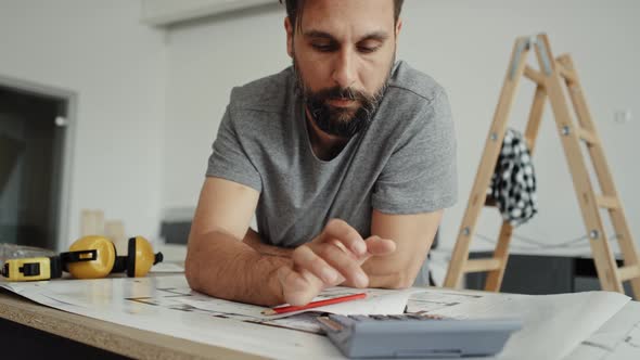 Handheld video of carpenter calculating something on the calculator ...