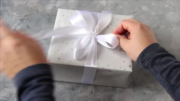 Hands untie a bow on a present on a table, Stock Footage | VideoHive