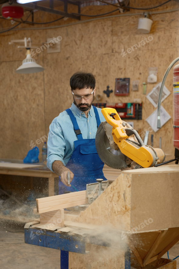 Skilled carpenter sawing wood plank using round circular saw at ...