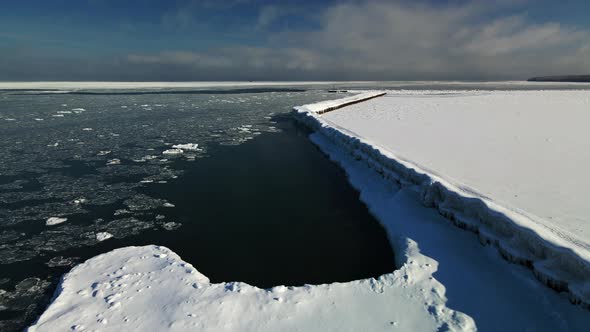 Drone footage along snow covered pier and ice chunks on Lake Huron in ...