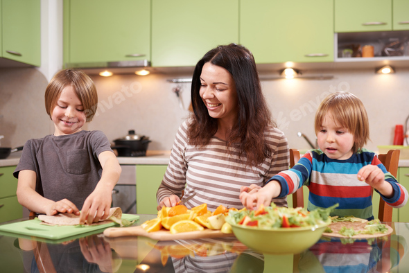Happy family preparing healthy food in the kitchen, mother and children ...