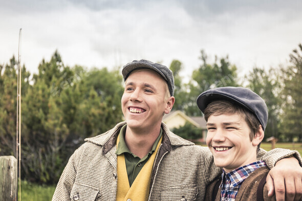 Man wearing flat cap, arm around boy looking away smiling Stock Photo ...