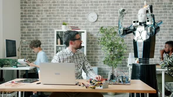 Robotics Engineer Building and Testing Robot in Office Using Wires and ...