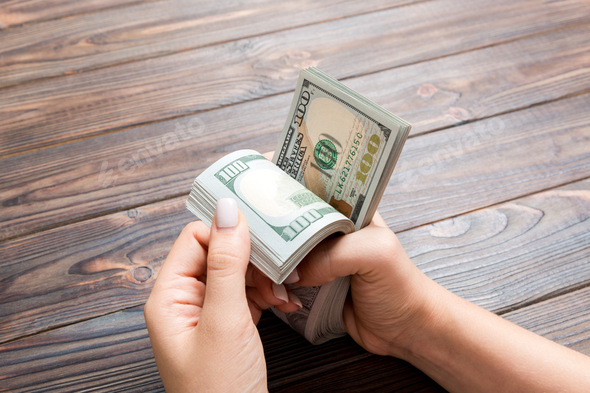 Perspective view of female hands counting money. One hundred dollar ...