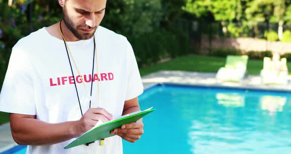 Smiling lifeguard writing on clipboard at poolside, Stock Footage ...
