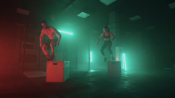 A Man and a Woman Jump Over a Box Performing a Burpee, Stock Footage