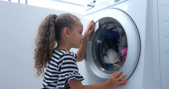 Child Looks Inside the Washing Machine. Cylinder Spinning Machine ...