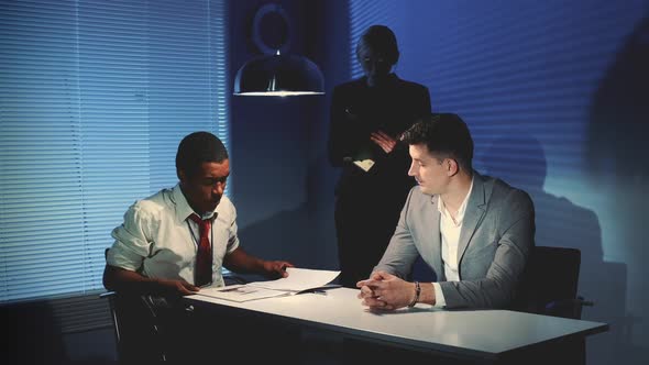 Medium Shot of African Detective Questioning Suspect Caucasian Man in ...