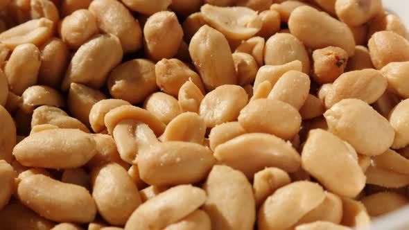 Roasted and salted groundnut snack food in a bowl slow tilting ...