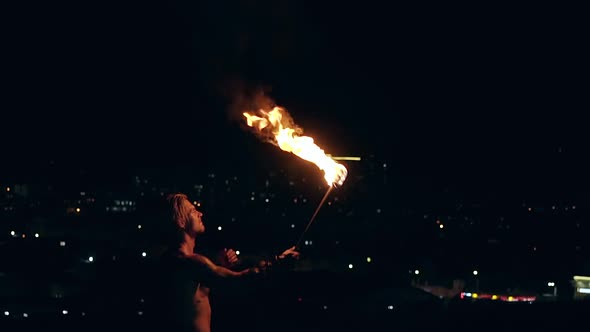 Young Blond Male Breathes Out Large Stream of Fire with Torch on Black ...