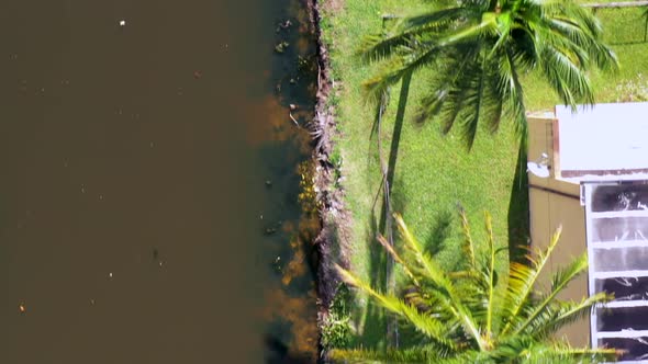 A top down view over a dirty water runoff behind residential homes with ...
