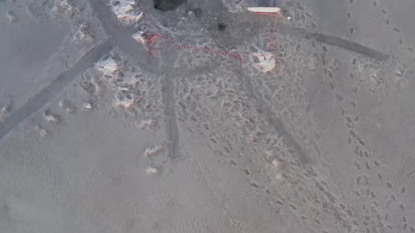 Red warning tape around triangle shaped ice hole on frozen lake. Aerial ...