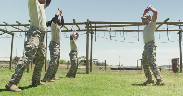 Fit diverse group of soldiers doing jumping jacks on army obstacle ...