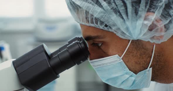 A Scientist in Sterile Clothing Looks Through a Microscope, Stock Footage