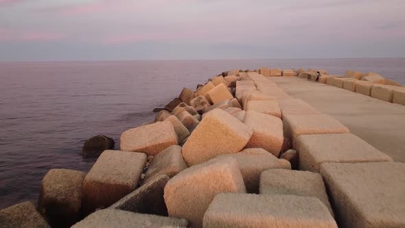 Low angle backwards shot of stony jetty of pier during beautiful summer ...