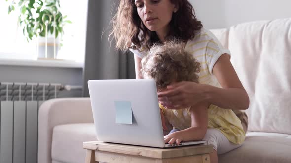 Mother Multitasking Using Laptop Computer at Home with Her Baby ...