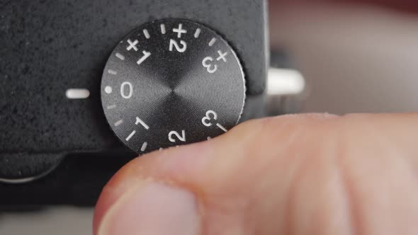 Adjusting the exposure compensation dial on a camera. Extreme close up ...