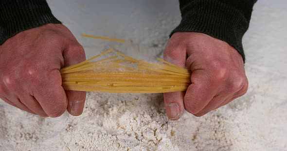 Hands of Man Breaking Spaghetti Pasta against Flour Background, Slow ...