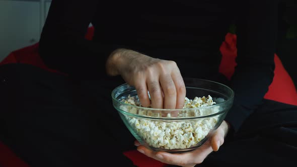 Close-up of a man's hand taking popcorn from a large glass cup. A man ...