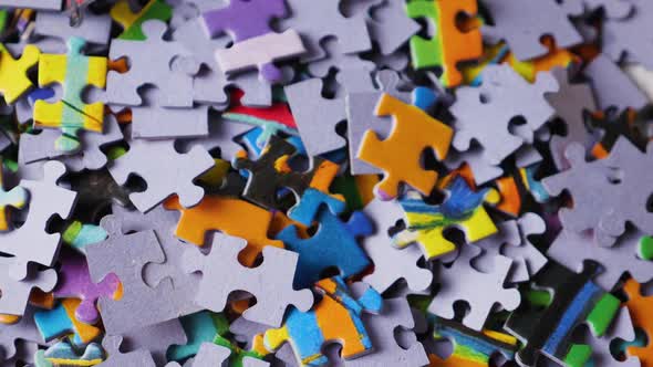 Close-up on a pile of jigsaw puzzle pieces falling with colorful pieces ...