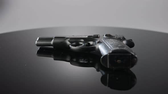 Gun Control. Studio shot of a 9mm gun rotating on a reflective surface ...