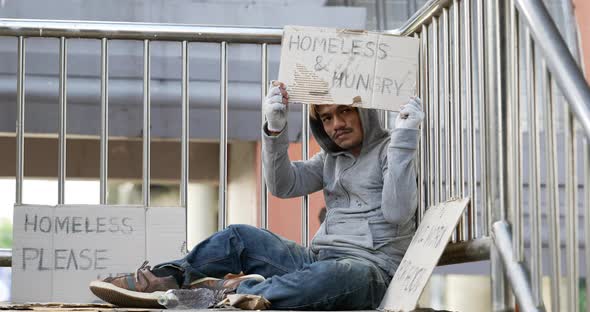 Homeless man sitting and holding homeless and hungry sign on the ...