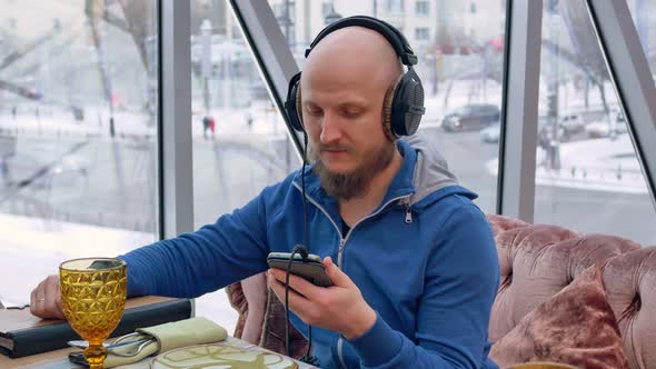 A Young Man Without Hair with a Beard Spends His Leisure Time in a ...