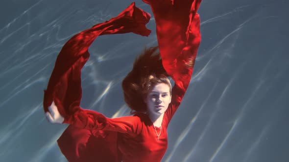 Attractive Redhaired Young Woman Swims Beautifully Underwater in a Red ...