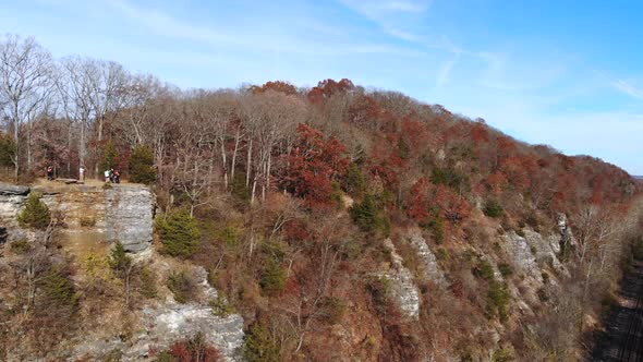 Aerial wide angel of hikers along cliffside with railroad tracks down ...