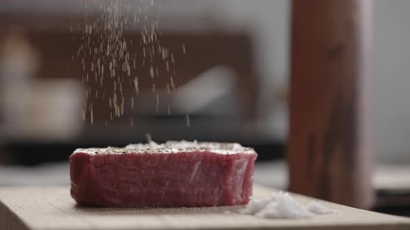 Slow Motion Slide Shot of Man Seasoning Raw Beef Steak Resting on Oak ...
