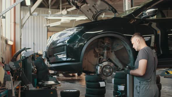 Sliding Shot of Auto Mechanic Checking SUV Suspension of a Lifted Car ...