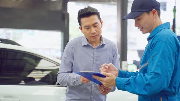 Asian automotive mechanic explain car condition to client in garage ...