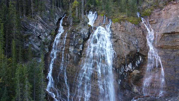 Aerial 4k footage of a triple waterfall in the Rocky Mountains. Slowly ...