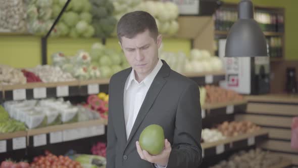 Middle Shot of Concentrated Caucasian Man Choosing Pomelo in Grocery ...