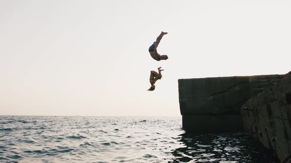 Young Woman and Man Synchronously Doing Frontflip From a Pier Into the ...