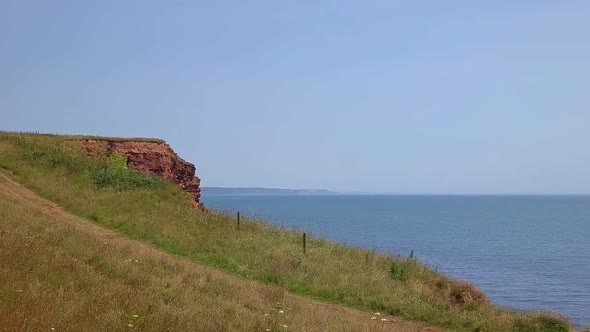 Aerial Pull Back away from the ocean along a grassy bluff, STATIC CROP ...