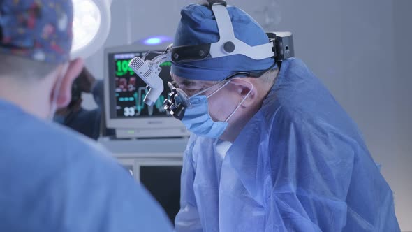 The Surgeon Wearing Special Optics Oversees the Operation, Stock Footage