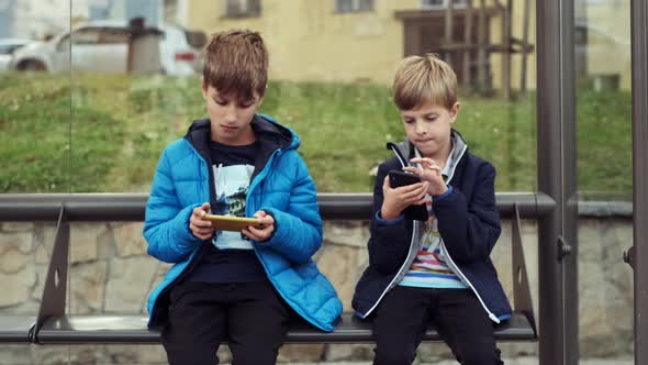 Two Boys Are Sitting At The Bus Stop., Stock Footage | VideoHive