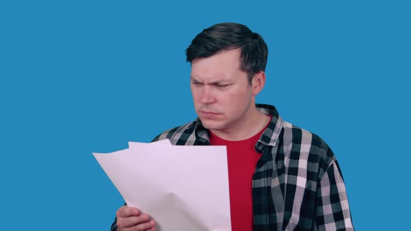 Surprised man looking at paper, reading document, over blue background ...