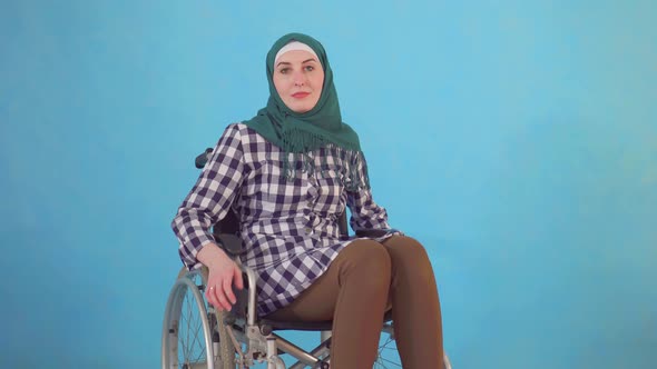 Portrait of a Young Muslim Woman Disabled in a Wheelchair on a Blue ...