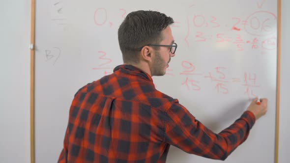 Close Shot of Young Man Math Teacher with Red Shirt and Glasses Writing ...