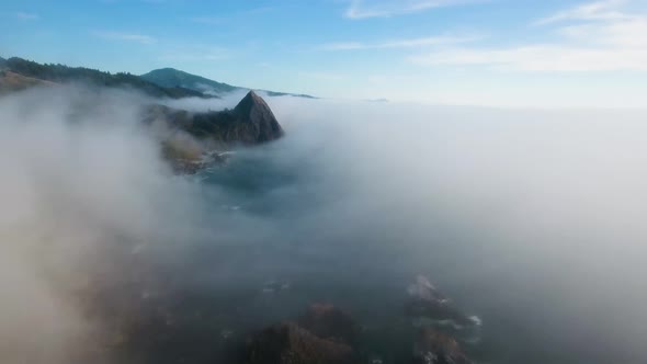 AERIAL: Pushing through a mist filled day towards a mountain on the ...