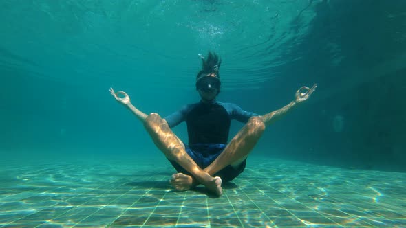 Slowmotion Underwater Shot of a Young Man in a Yoga Pose Meditating on ...