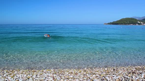 Young man with swarthy skin and black hair is swimming in the sea ...