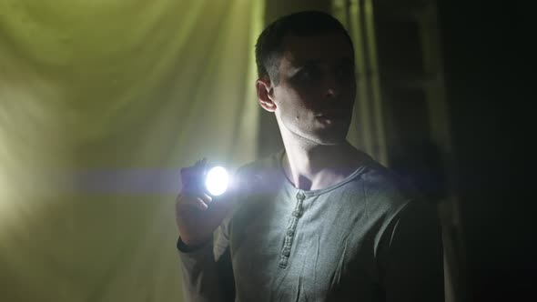 Man with a Flashlight Looking Around in a Dark Room, Stock Footage