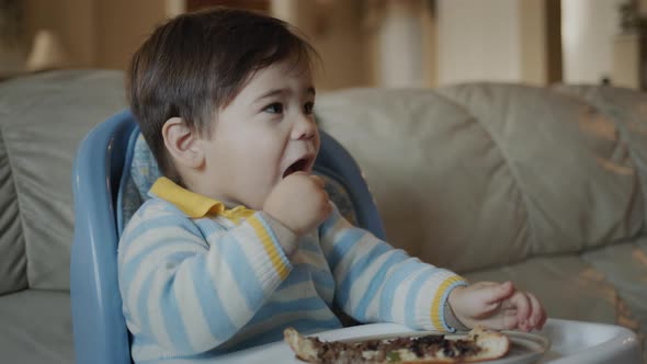 Asian Baby Eats Pizza Sits on the Baby's Feeding Table, Stock Footage
