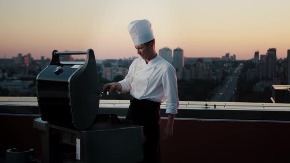 A professional Chef prepares a barbecue on the rooftop of a skyscraper ...